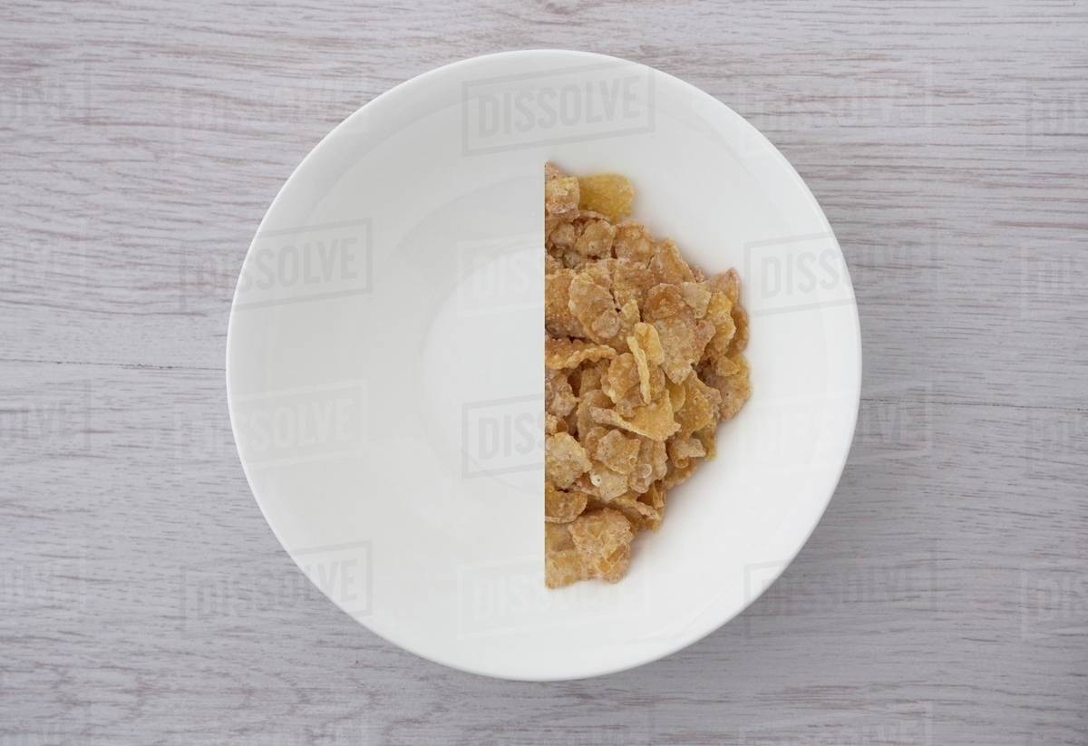 A halved portion of cornflakes in a white bowl (view from above ...