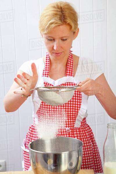 A woman sieving flour into a mixing bowl - Royalty-free Stock Photo ...
