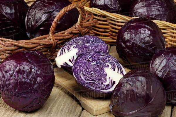 Red cabbage in baskets and on a chopping board, whole and cut in half ...