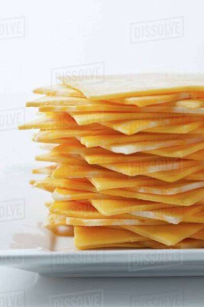 Stack of yellow American and Colby jack cheese on a white plate - Stock ...