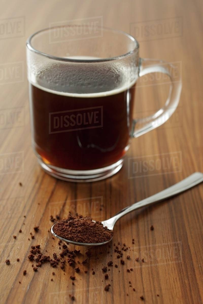 A cup of instant coffee and a spoonful of instant coffee powder ...