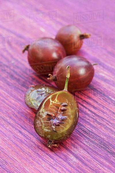 Red gooseberries, one sliced, on a wooden surface - Royalty-free Stock ...