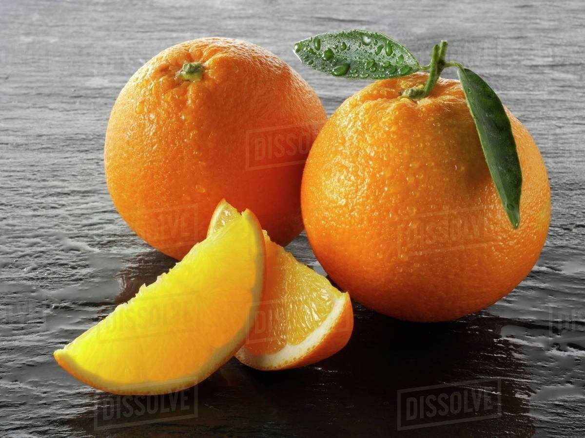 Two whole oranges and two oranges wedges - Stock Photo - Dissolve