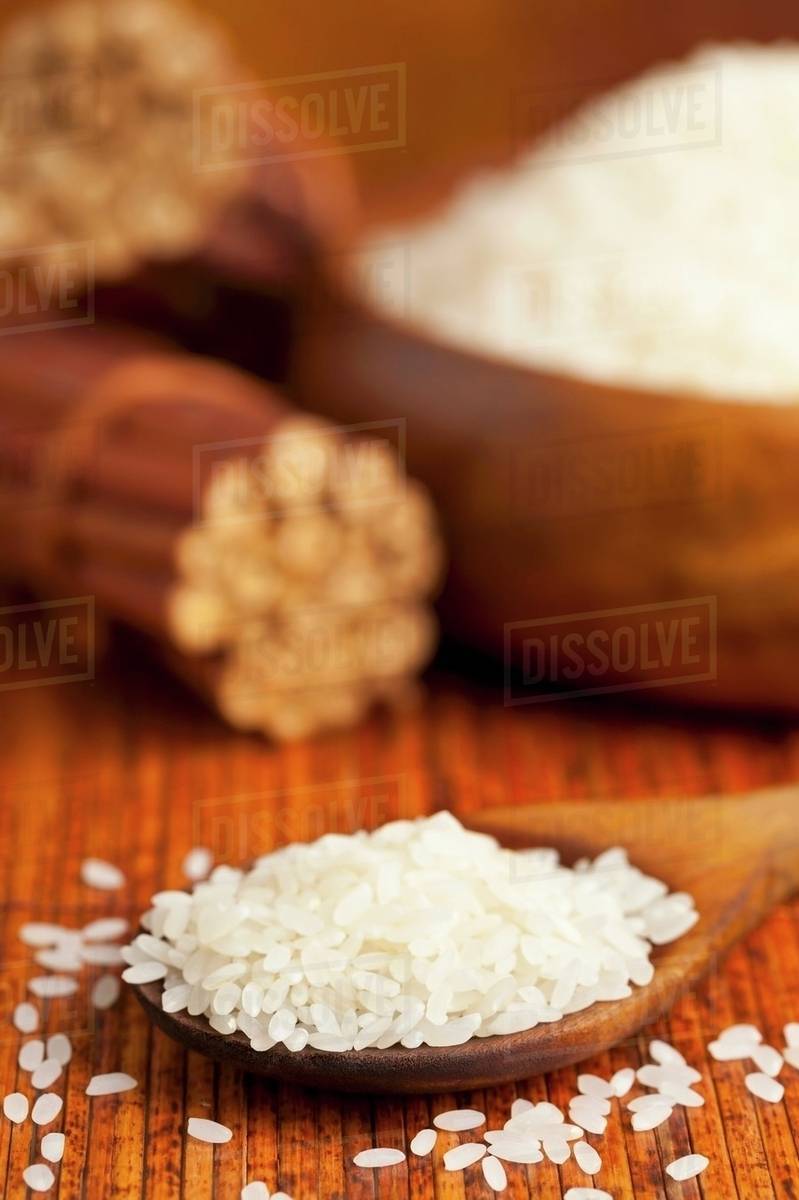 Raw sushi rice on a wooden spoon - Stock Photo - Dissolve