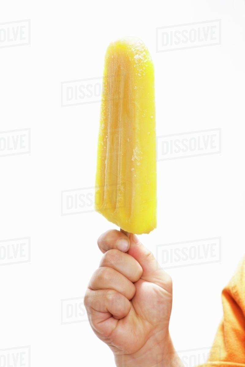 Hand holding an orange ice lolly - Royalty-free Stock Photo | Dissolve
