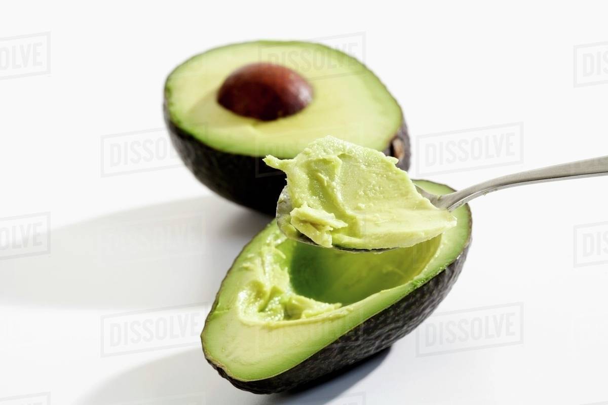 Hollowing out an avocado with a spoon - Royalty-free Stock Photo | Dissolve