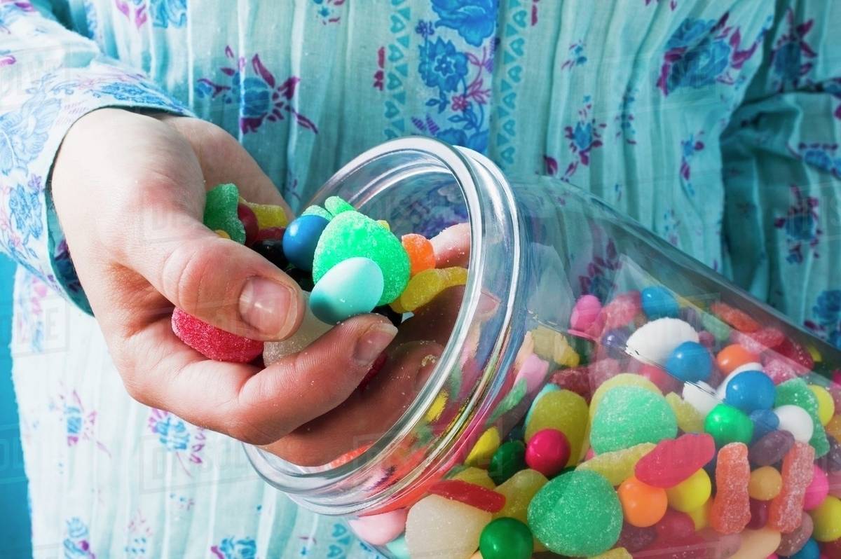 Hand taking sweets out of jar - Royalty-free Stock Photo | Dissolve