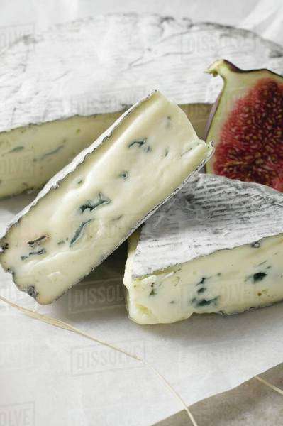 Blue cheese with pieces cut and half a fig on paper - Stock Photo ...