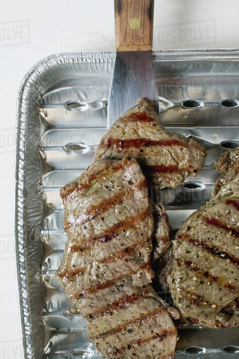 Grilled meat in aluminium grill tray (overhead view) - Royalty-free ...