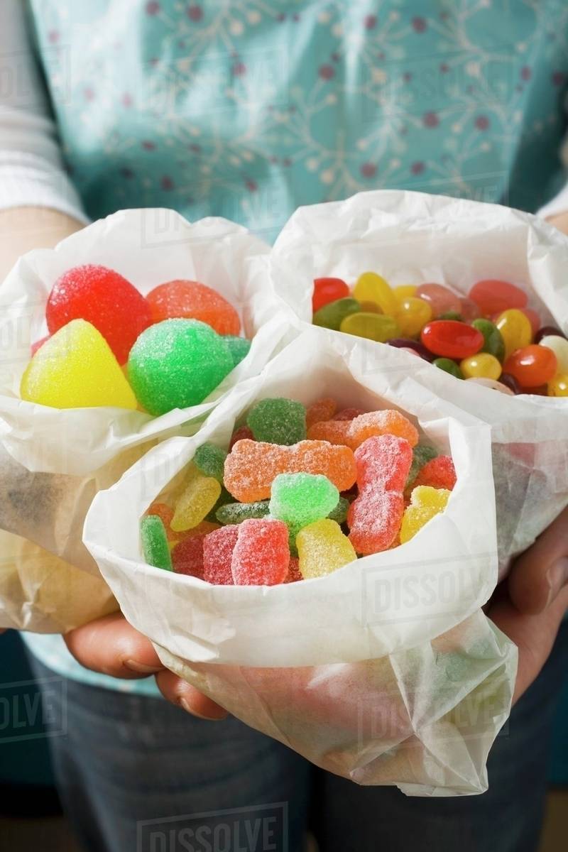 Hands holding three paper bags of jelly sweets - Royalty-free Stock ...