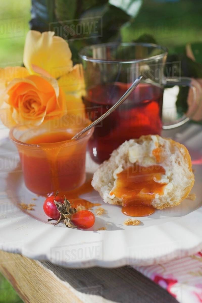 Rose hip jam on bread roll, rose hip tea, yellow rose - Stock Photo ...