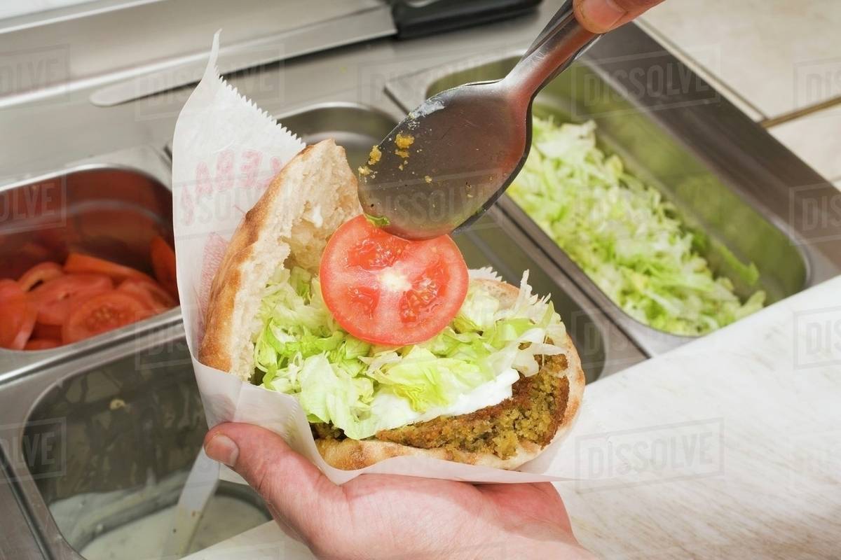 Adding tomato to pita bread filled with falafel - Royalty-free Stock ...