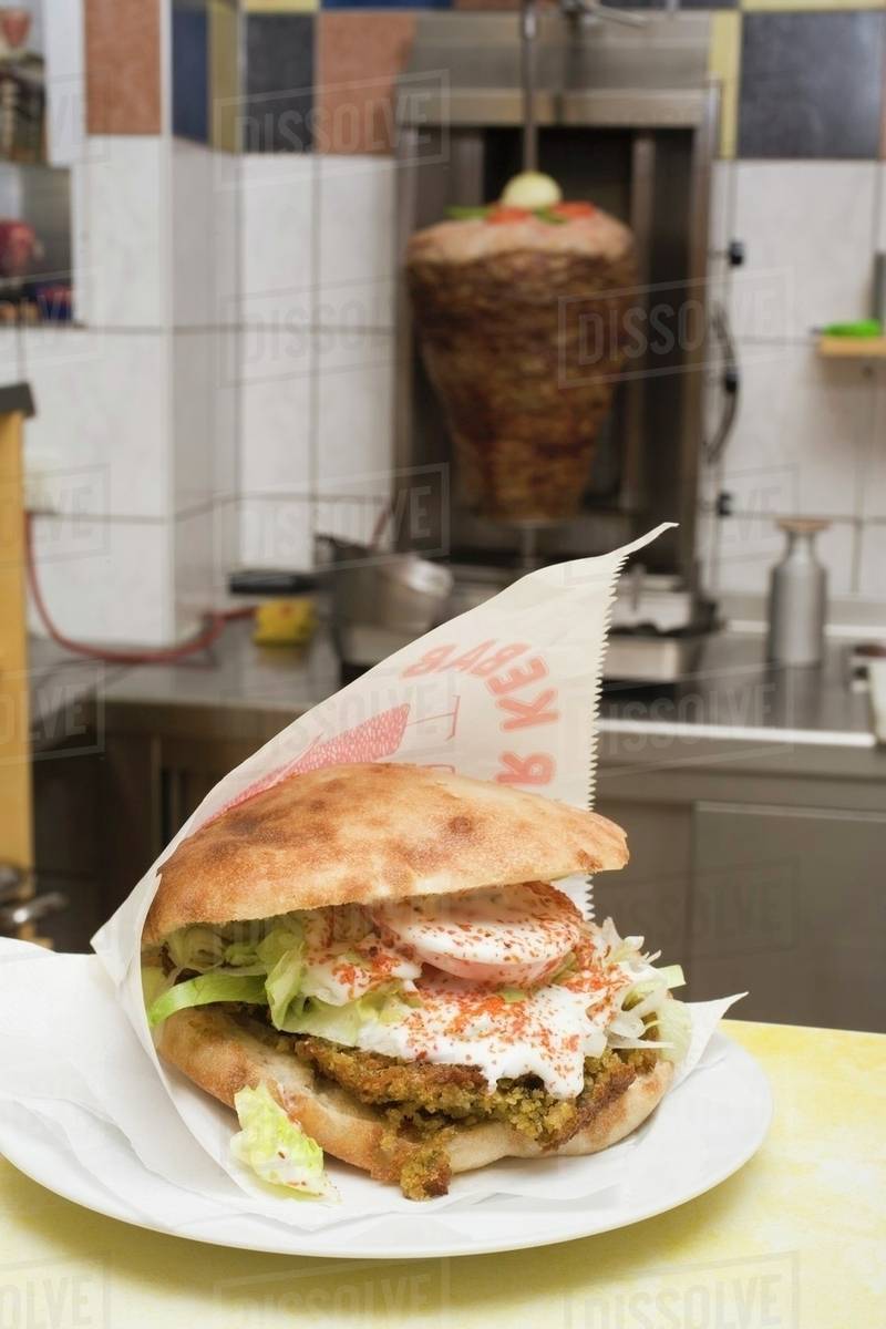 Pita bread with falafel on counter in front of doner grill - Stock ...