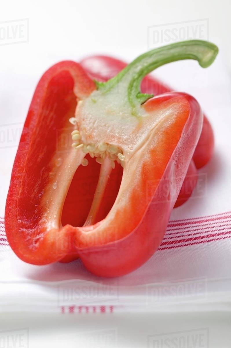 Red pepper, halved, on tea towel - Stock Photo - Dissolve