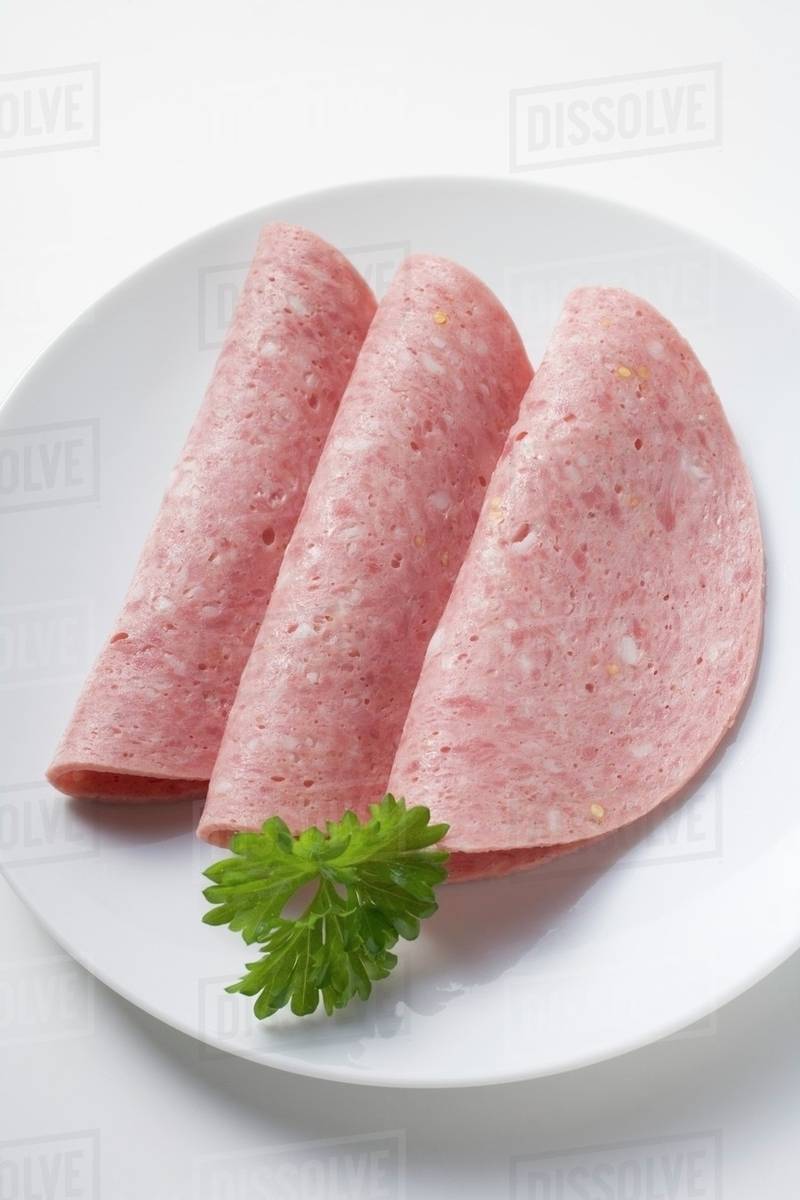 Three slices of Bierwurst (beer sausage) on plate - Stock Photo - Dissolve