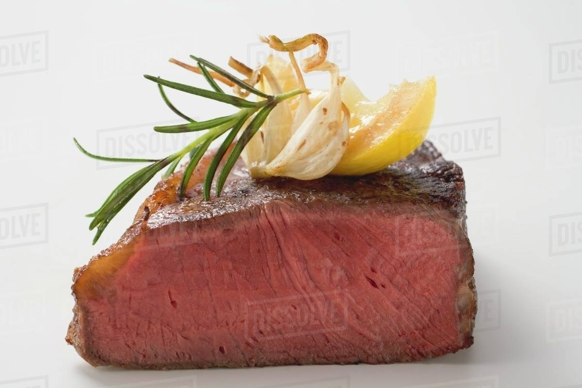 Beef steak, showing cut edge, with garlic, rosemary, lemon - Royalty ...
