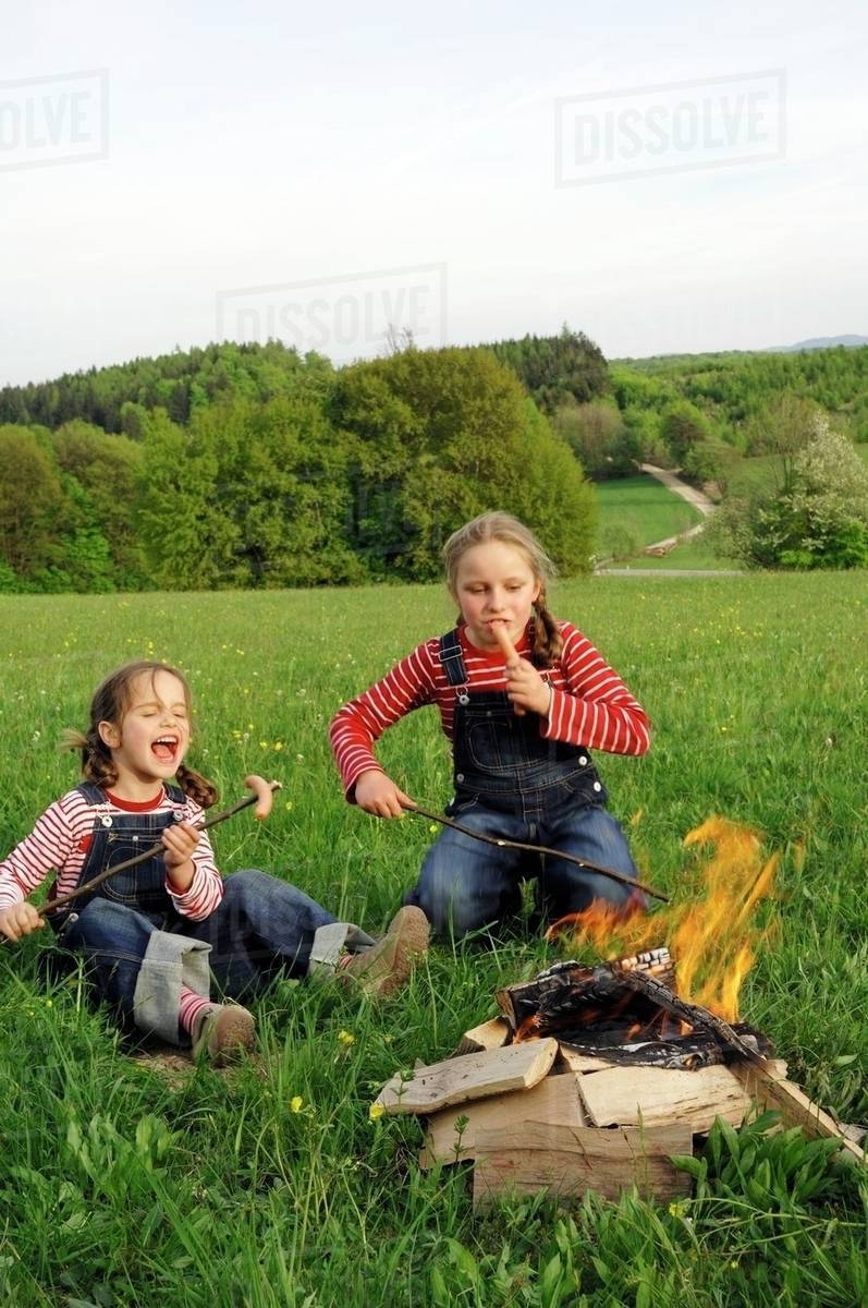 Two girls grilling sausages over a camp-fire - Royalty-free Stock Photo ...
