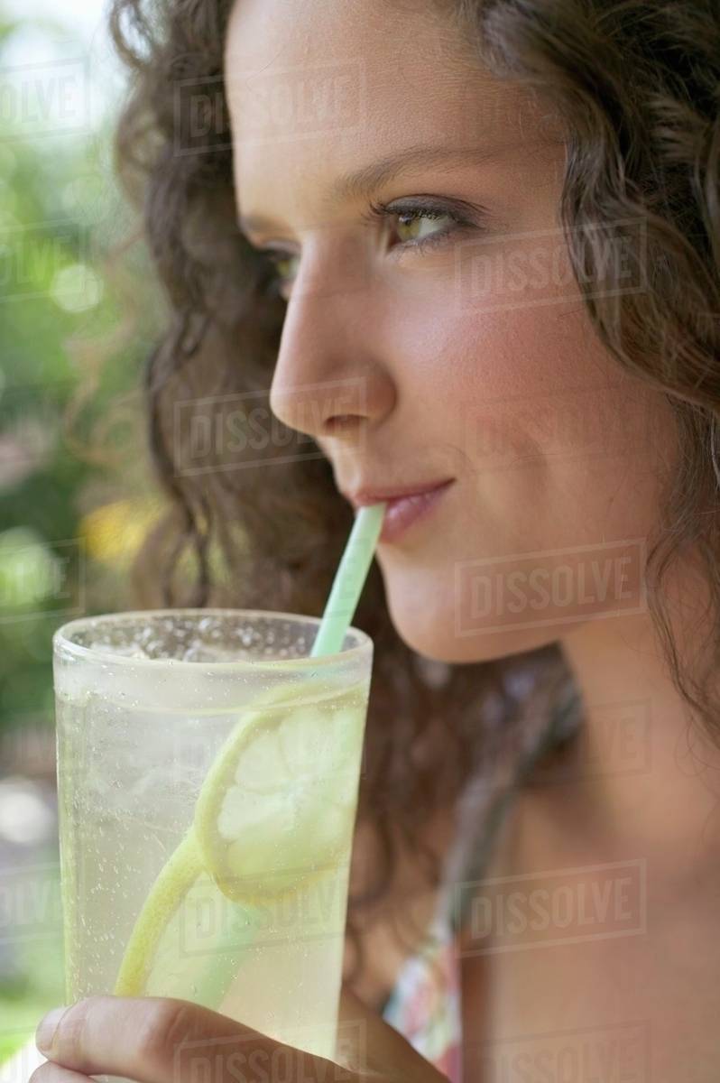 Young woman drinking lemonade through a straw - Stock Photo - Dissolve