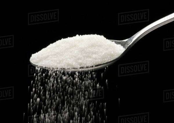 Sprinkling sugar from a tablespoon - Stock Photo - Dissolve