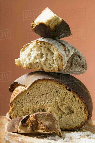 Rustic bread, two loaves with pieces cut off in a pile - Stock Photo ...