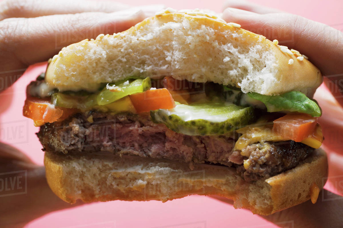 Hands holding cheeseburger with bites taken - Royalty-free Stock Photo ...