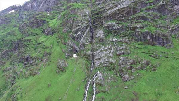 Aerial footage of long thin stream of water running down the slope of ...