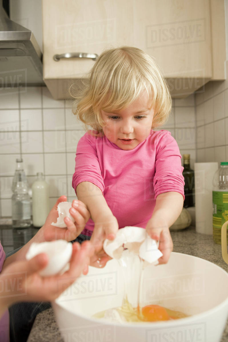 Girls pouring egg yolk in mixing bowl - Stock Photo - Dissolve