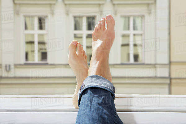 Germany, Berlin, Young woman feets on open window - Stock Photo - Dissolve