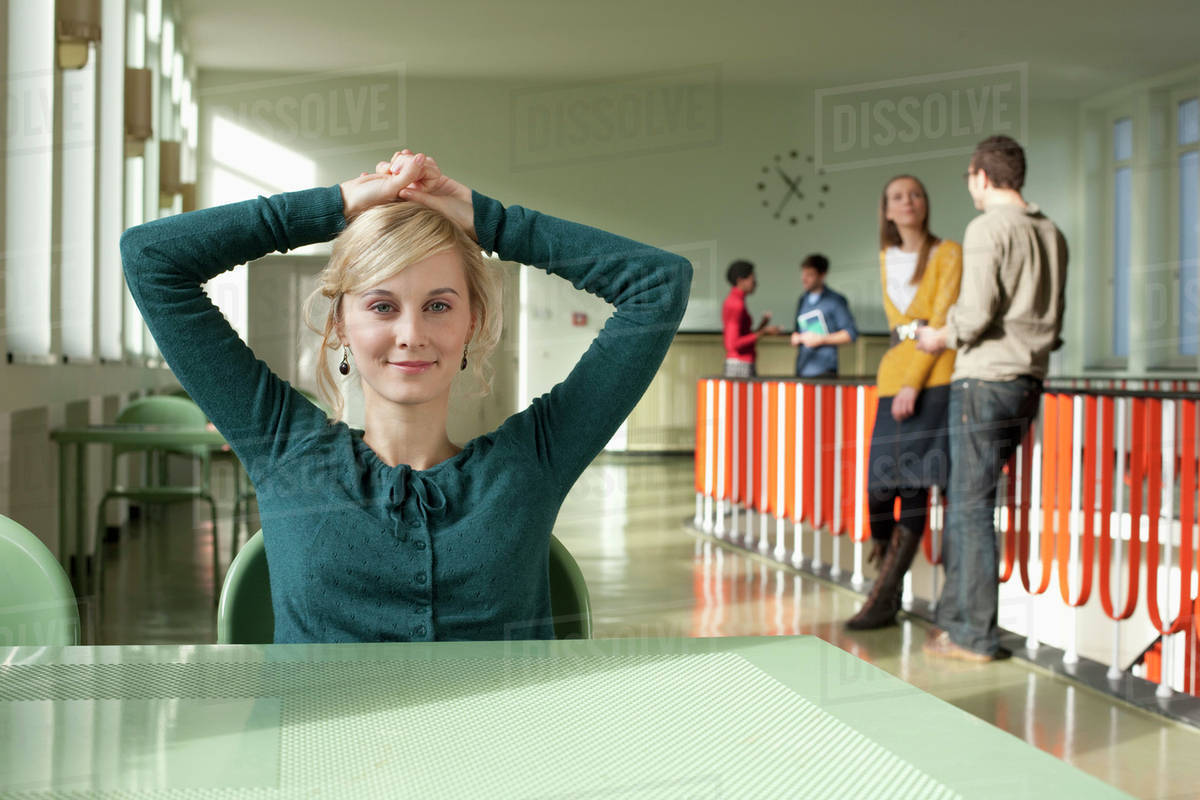 Germany, Leipzig, Woman sitting in hallway, students standing in ...