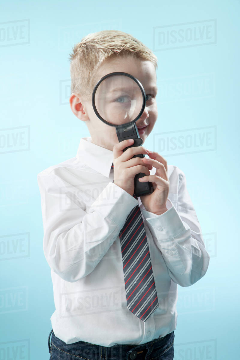 Boy watching through magnifying glass - Stock Photo - Dissolve