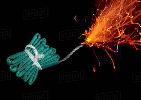 String of firecracker with lit fuse, close-up - Stock Photo - Dissolve