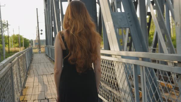 Girl with long beautiful hair walks along the railway bridge - Stock ...