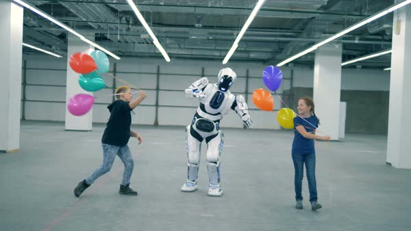 Android and children dance with balloons. Modern cyborg with children ...