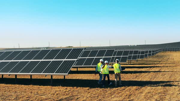 Solar power plant workers, solar energy industry concept. Three workers ...