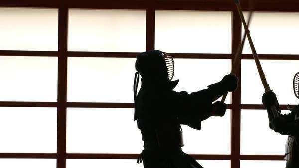 Kendo athletes in full body armour fighting in front of rice paper ...