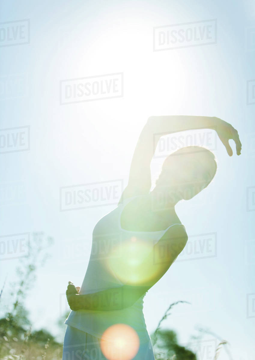 Woman standing, stretching arm over head, in sunshine - Royalty-free ...
