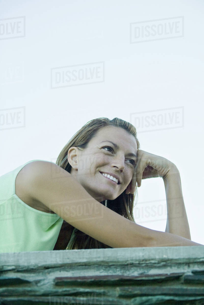 Woman smiling, leaning head against hand and looking away, low angle ...