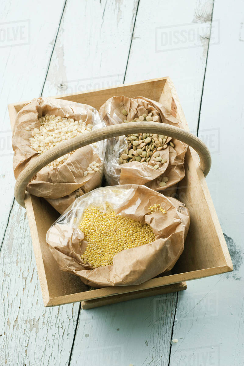 Bags of lentils, millet and short grain white rice in wooden basket ...