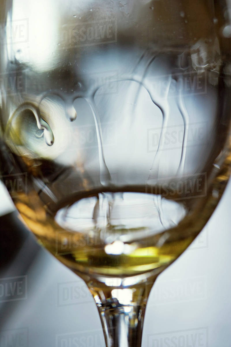 White wine dripping down inside of wine glass, extreme close-up ...