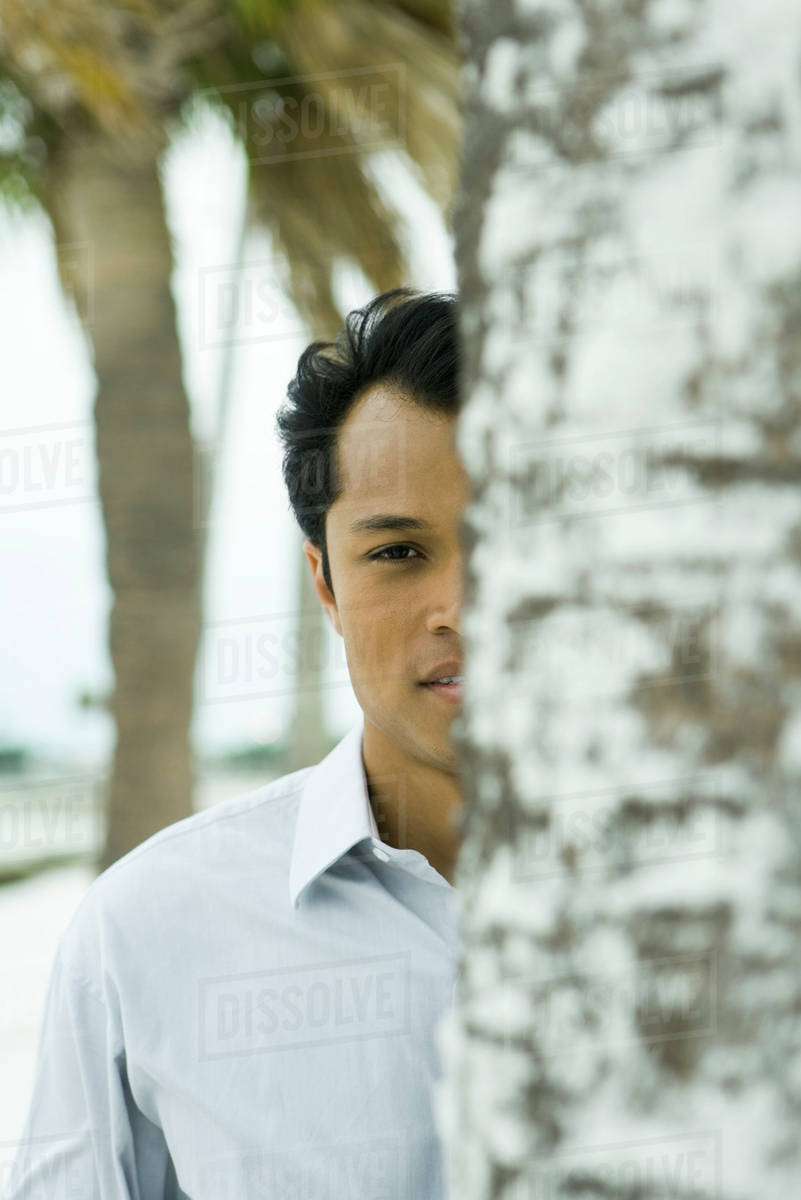 Man behind tree trunk, looking at camera - Royalty-free Stock Photo ...