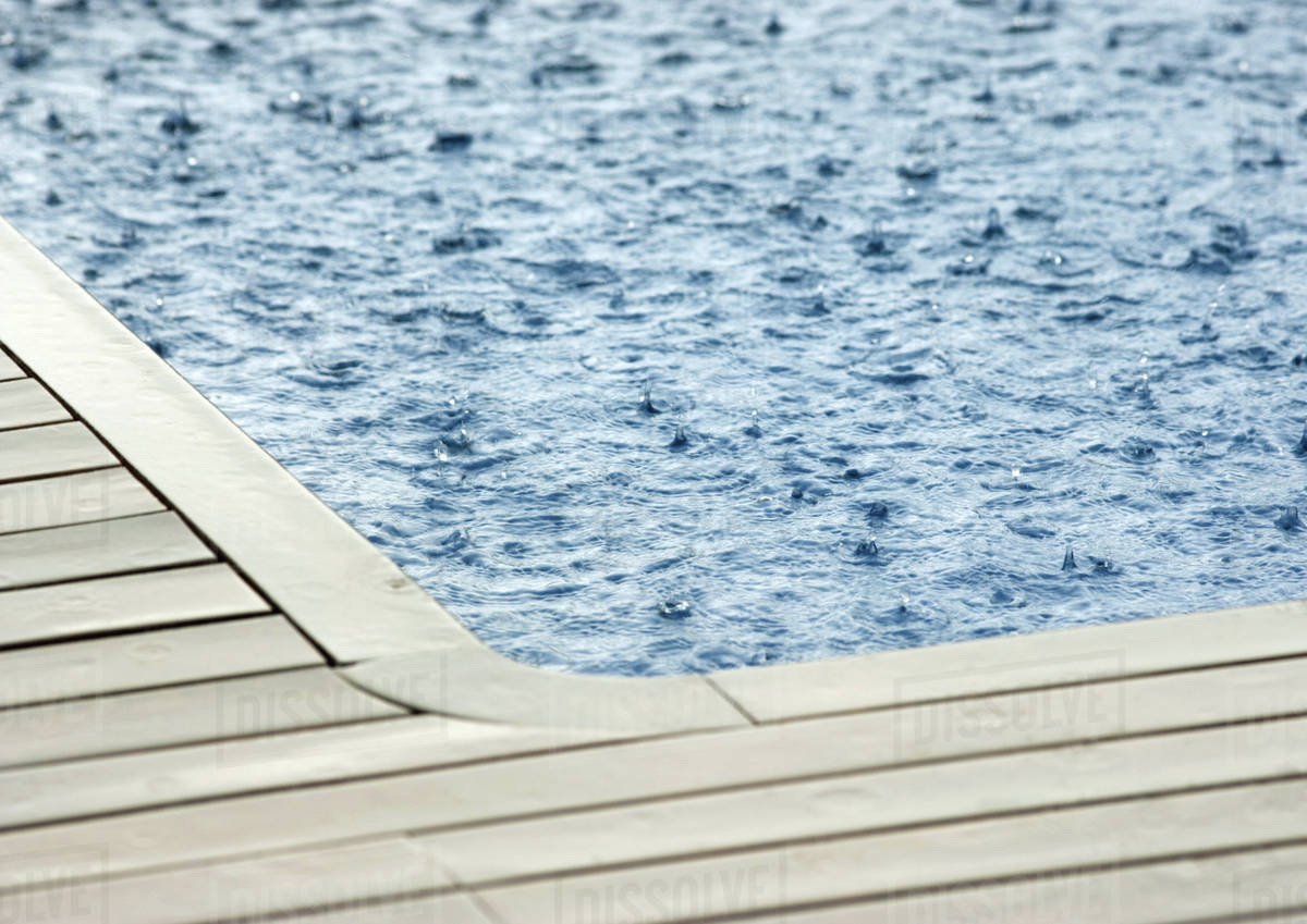 Rain falling on surface of swimming pool - Stock Photo - Dissolve