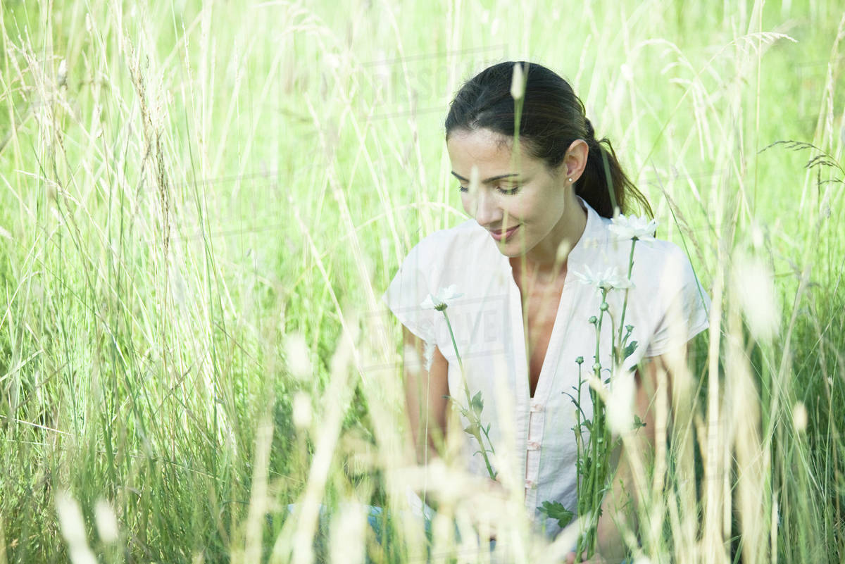 Woman in field, looking down - Royalty-free Stock Photo | Dissolve