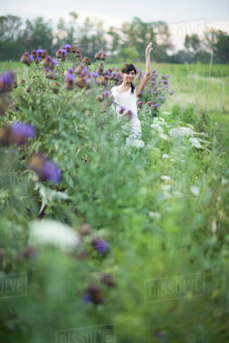 Young woman standing in flower garden, waving, in mid distance - Stock ...