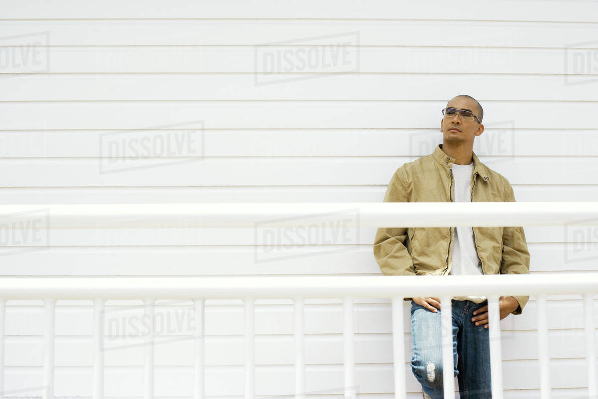 Man leaning against wall, hands on hips, looking away - Royalty-free ...