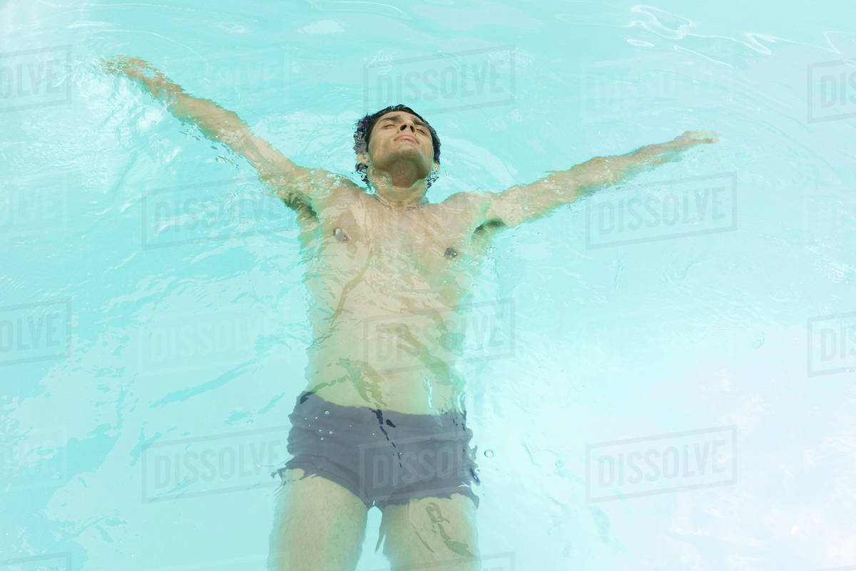 Man floating on back in swimming pool - Stock Photo - Dissolve