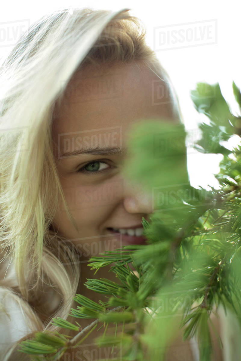 Smiling young woman behind tree branches, cropped - Royalty-free Stock ...