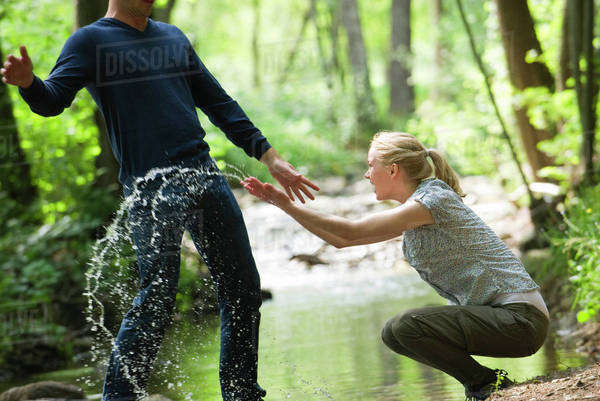 Young woman splashing water at man - Royalty-free Stock Photo | Dissolve