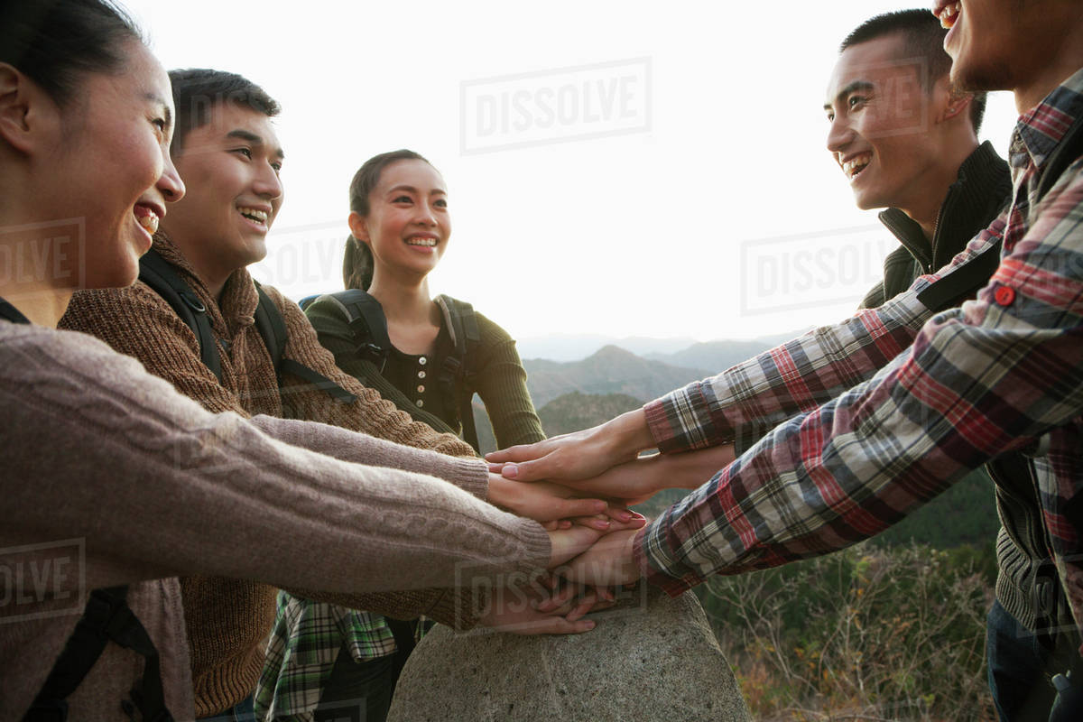 Group of young people smiling and holding hands together on the stone ...
