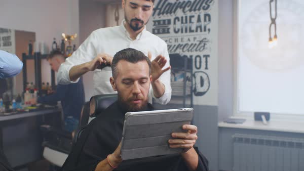 Businessman using tablet visiting barber shop for haircut - 4K Royalty ...