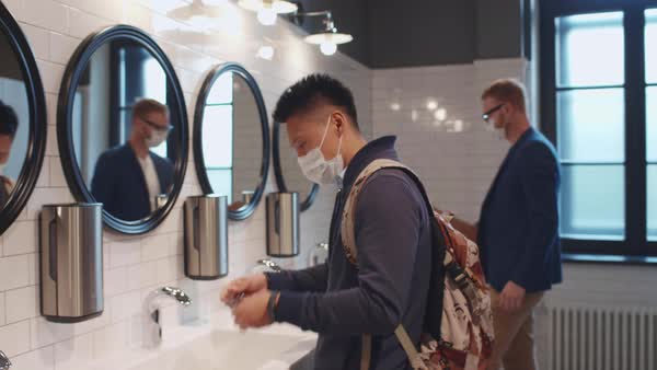 Male students in safety mask use university bathroom washing hands ...